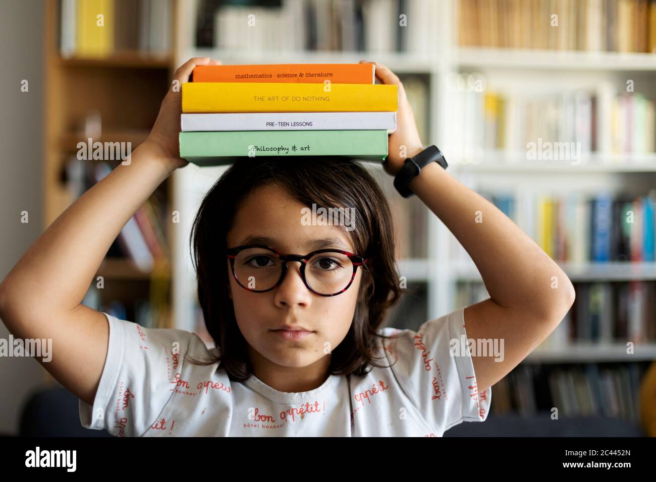 Portrait of serious boy with stack of books on his head Stock Photo - Alamy