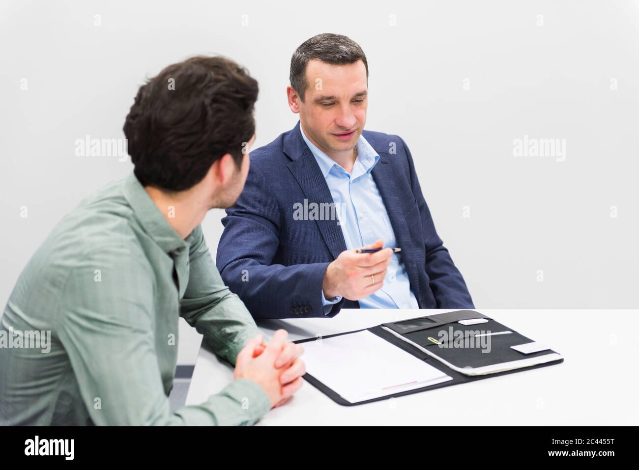 Two businessmen talking at desk in office Stock Photo - Alamy