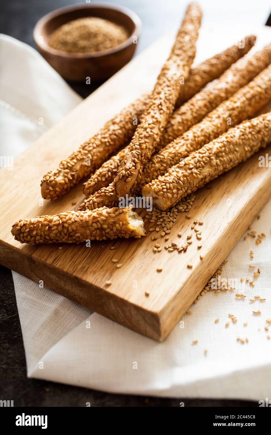 Cutting board and fresh Italian grissini breadsticks with sesame seeds ...