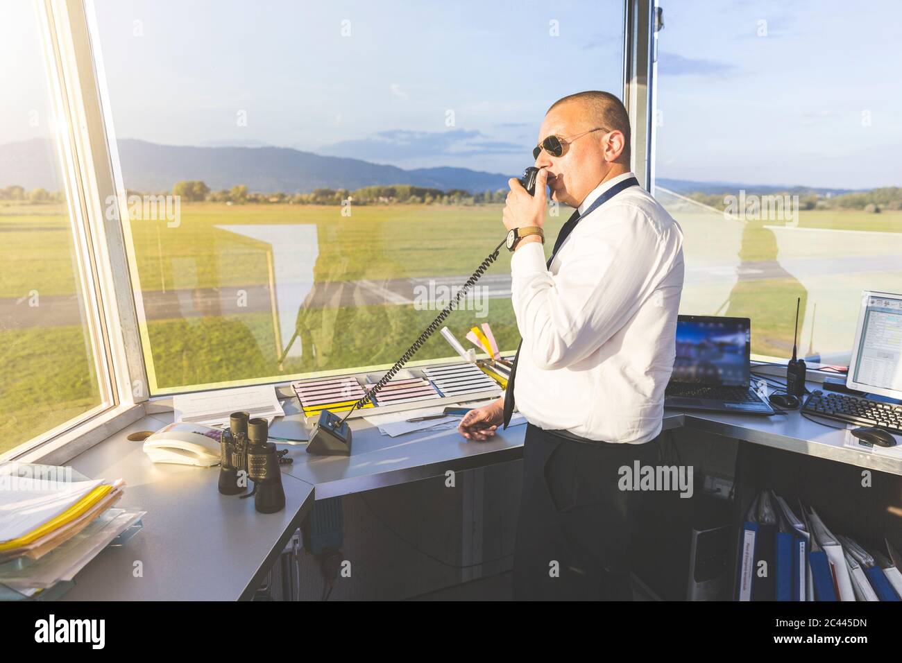 Pilot standing in control tower, talking on the radio Stock Photo - Alamy
