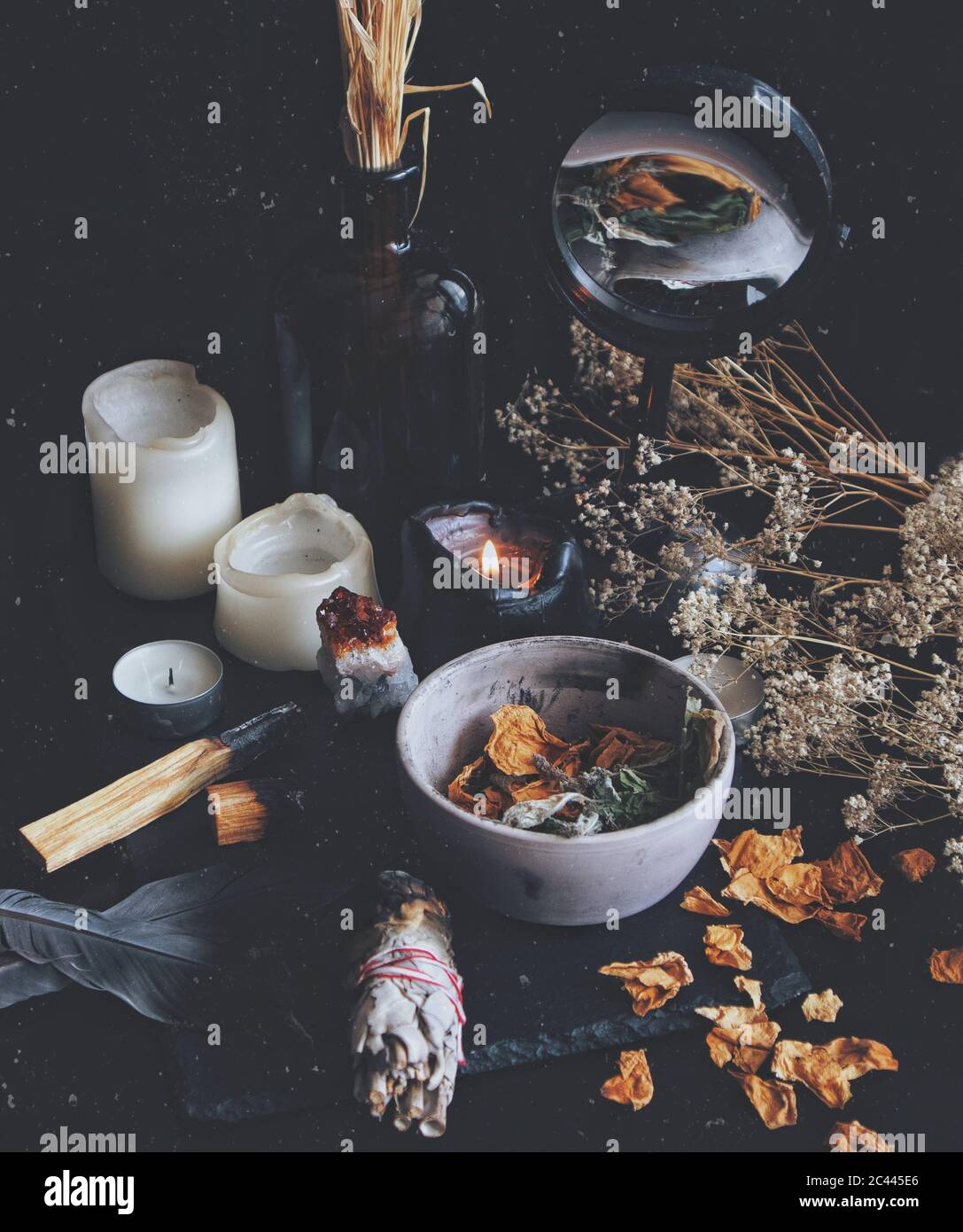 Dried plants, herbs and yellow rose flower petals in a grey, dirty clay ...