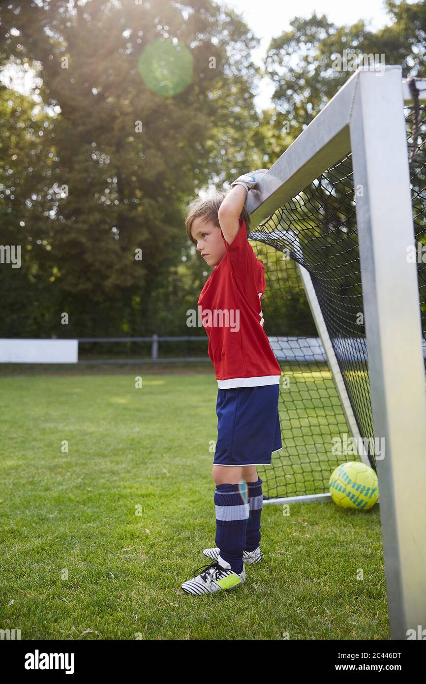 Boy in soccer uniform holding goal post at field Stock Photo - Alamy