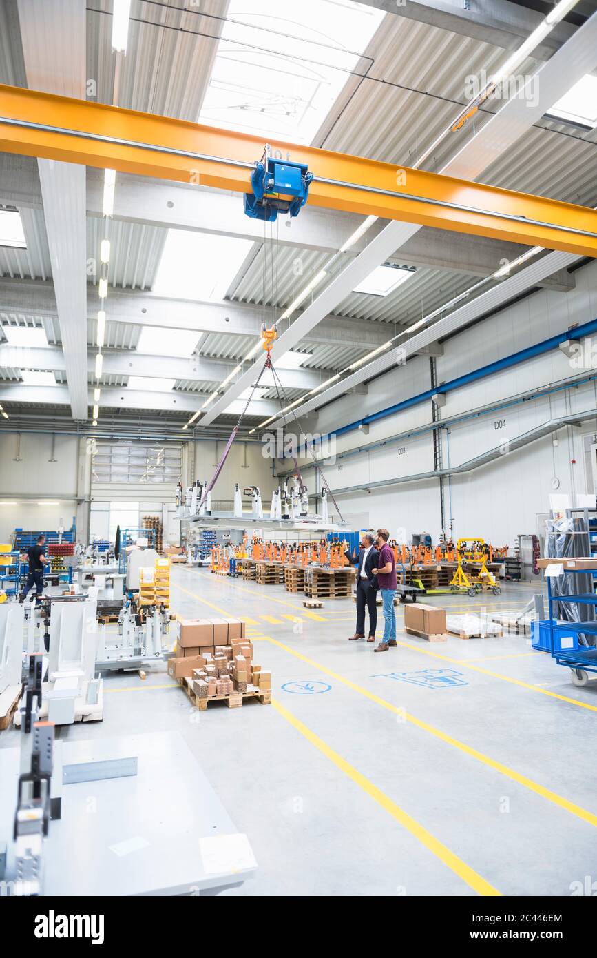 Two men with indoor crane in a factory Stock Photo - Alamy