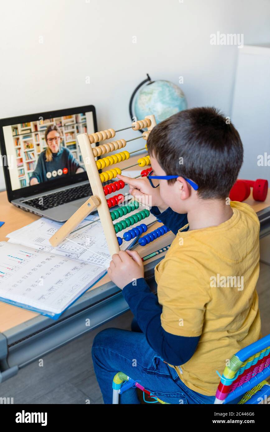 Elementary student using abacus with teacher on video call during ...
