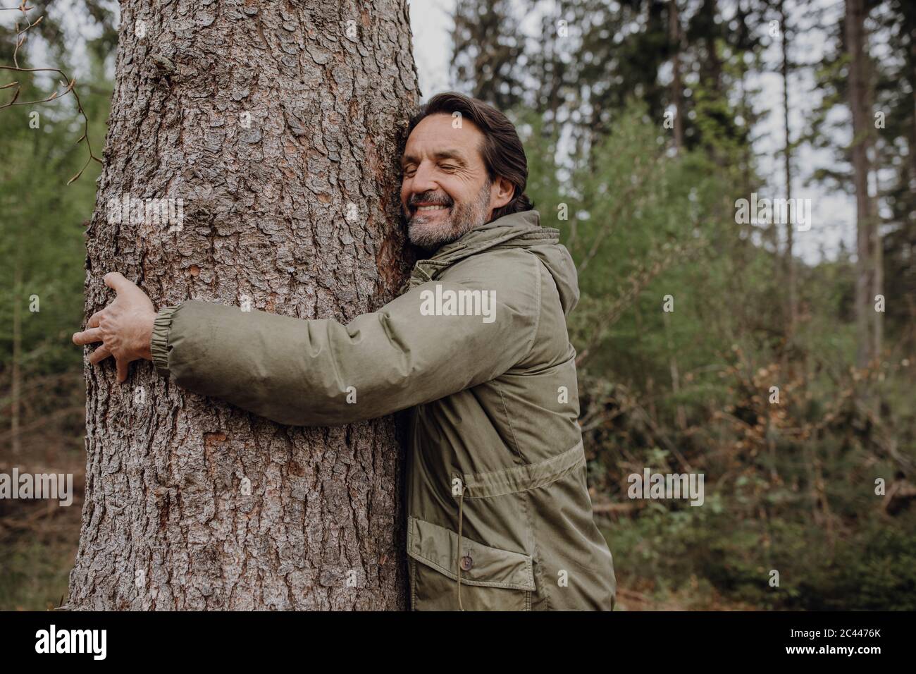Mature hiker hugging tree trunk Stock Photo - Alamy
