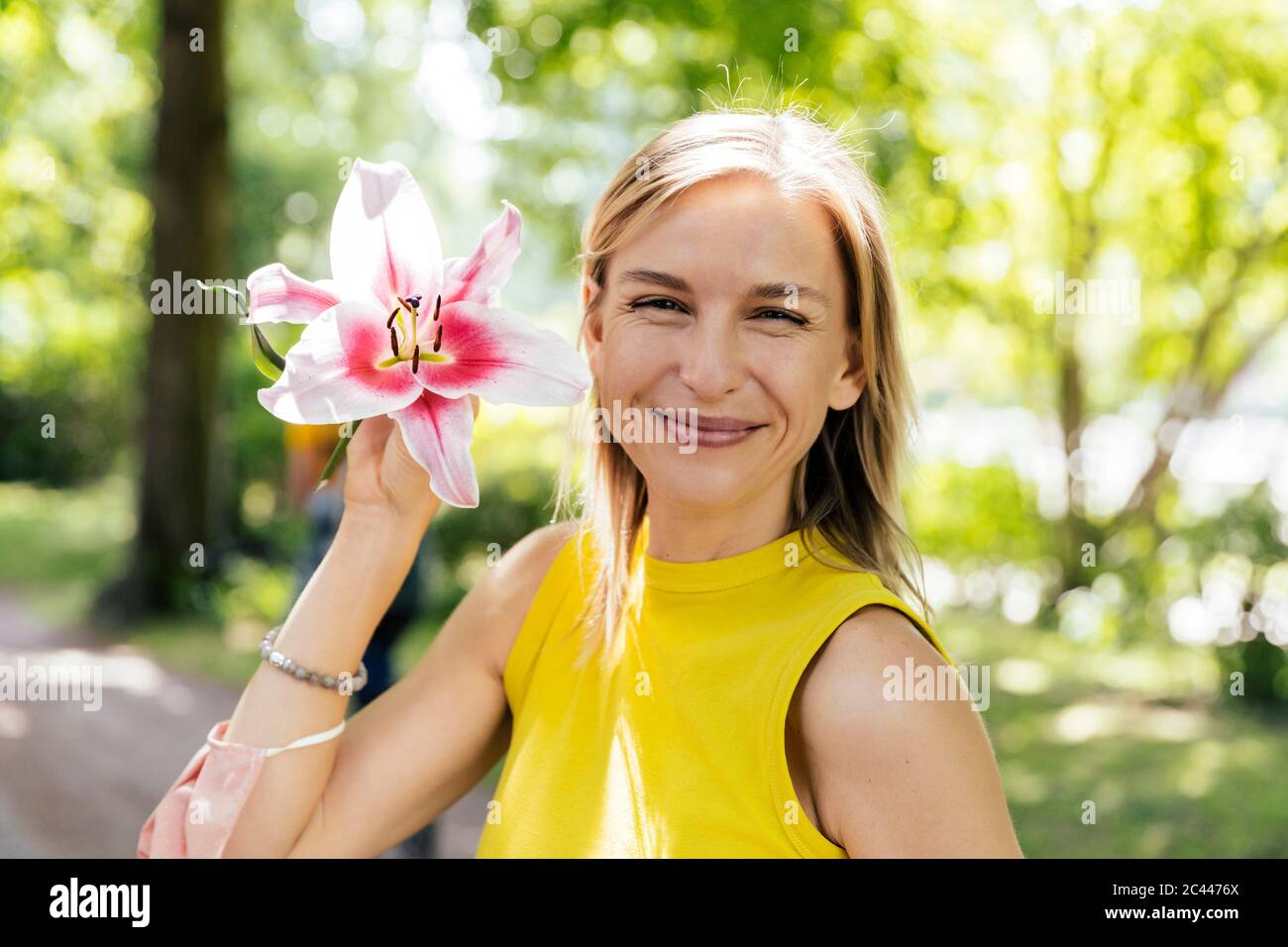 Portrait of smiling woman in nature holding lily flower Stock Photo - Alamy