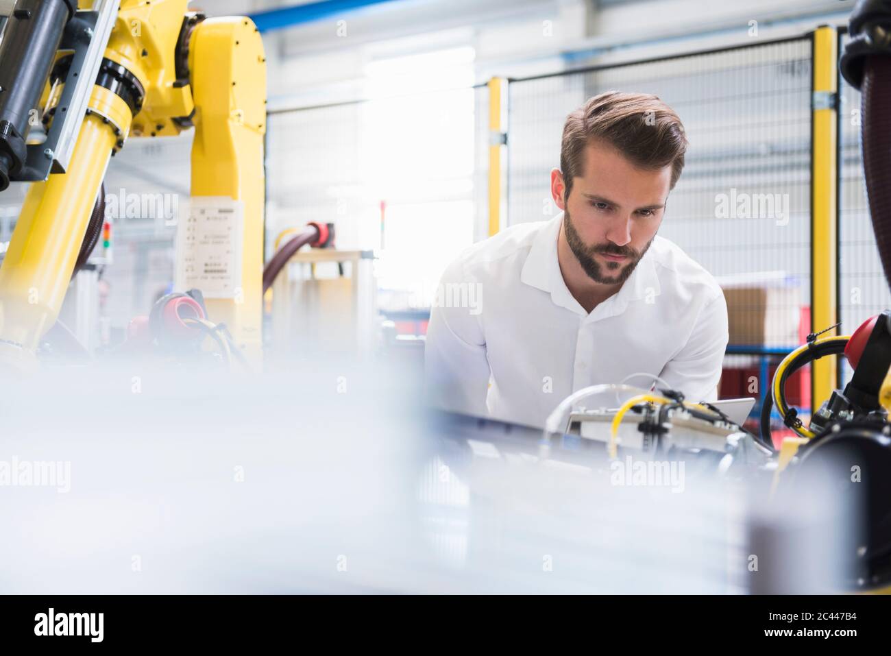 Engineer examining robotic arm in factory Stock Photo - Alamy