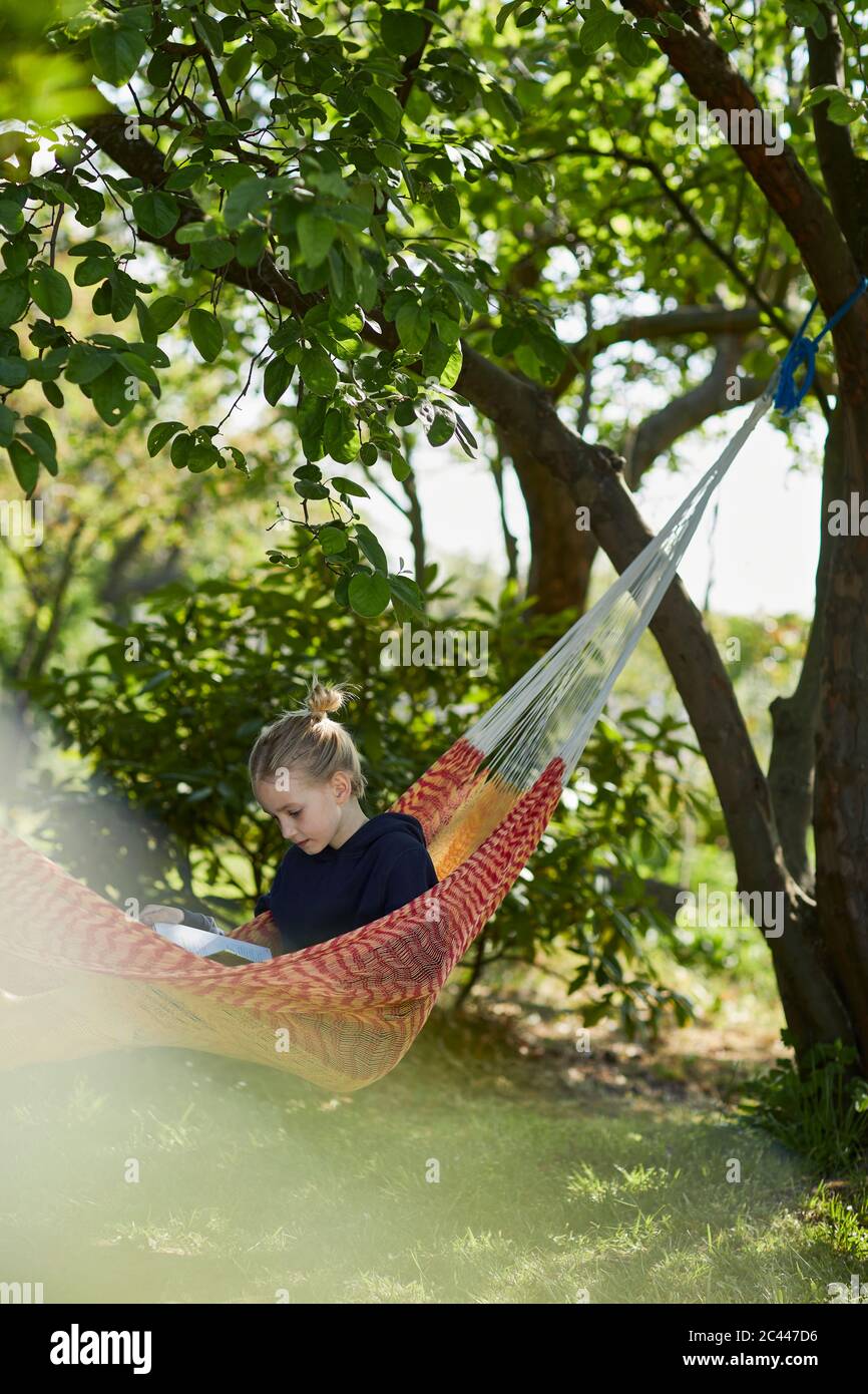 Girl in hammock reading a book Stock Photo - Alamy