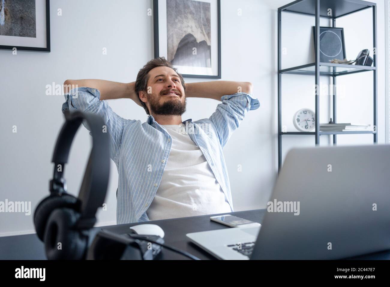 Man leaning back at desk Stock Photo - Alamy