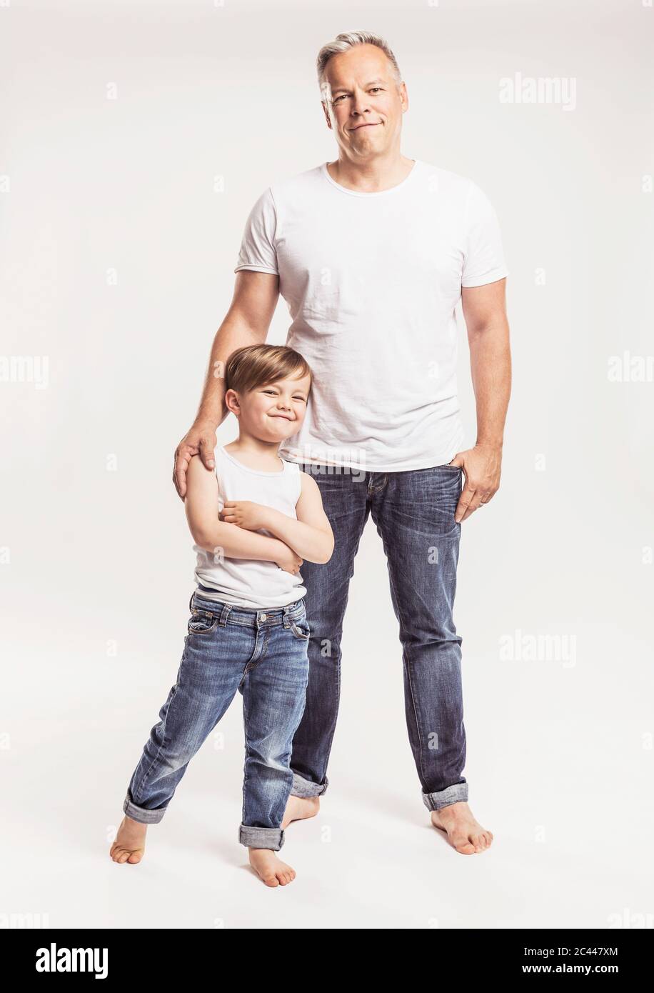 Portrait of father and his little son standing in front of white ...