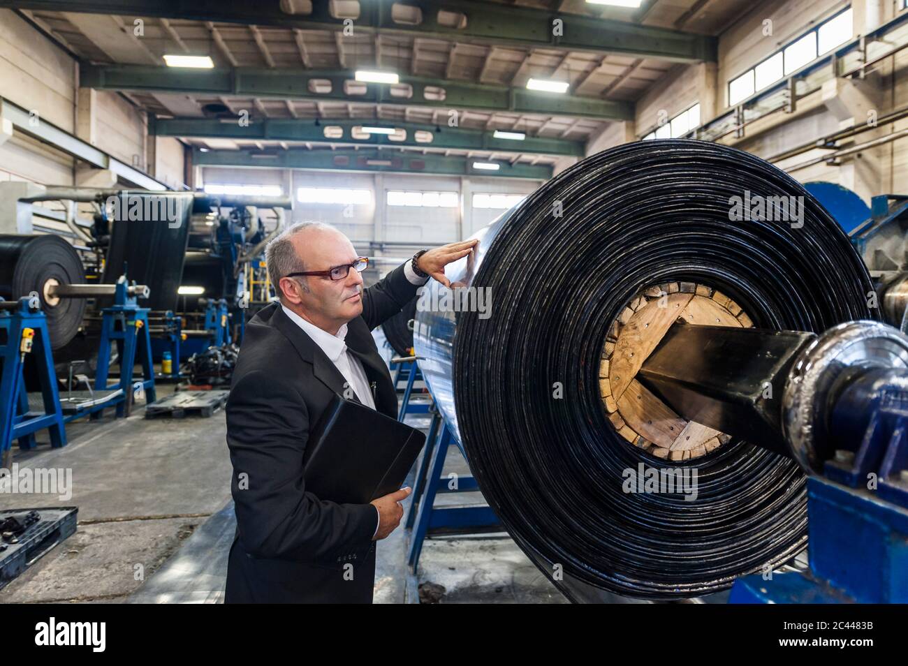 Senior businessman examining product in a rubber processing factory ...