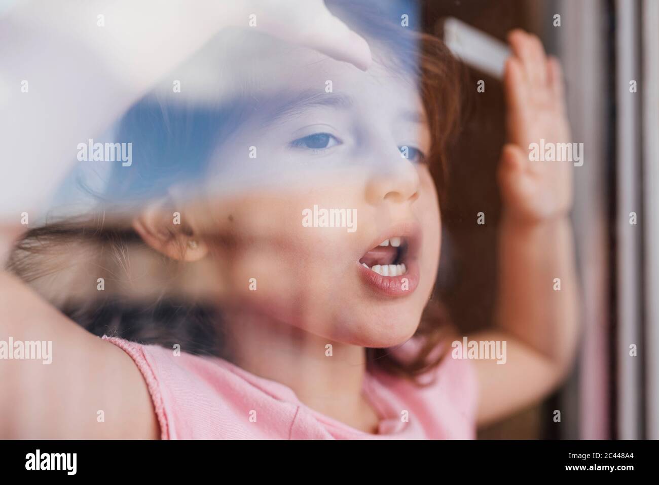 Portrait of little girl looking out of window Stock Photo - Alamy