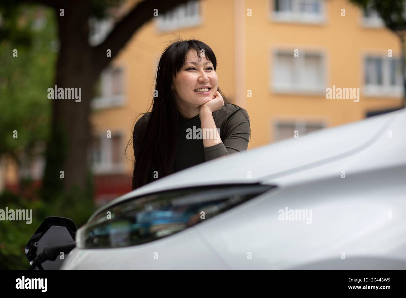 Carsharing, smiling woman charging an electric car Stock Photo - Alamy