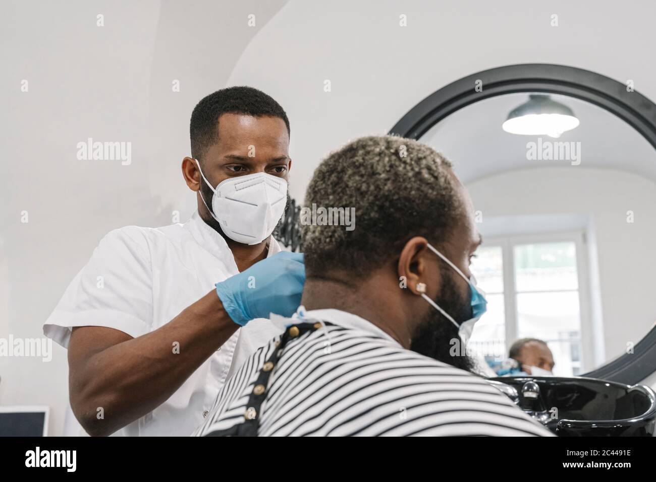Barber wearing surgical mask and gloves doing hair of customer Stock ...