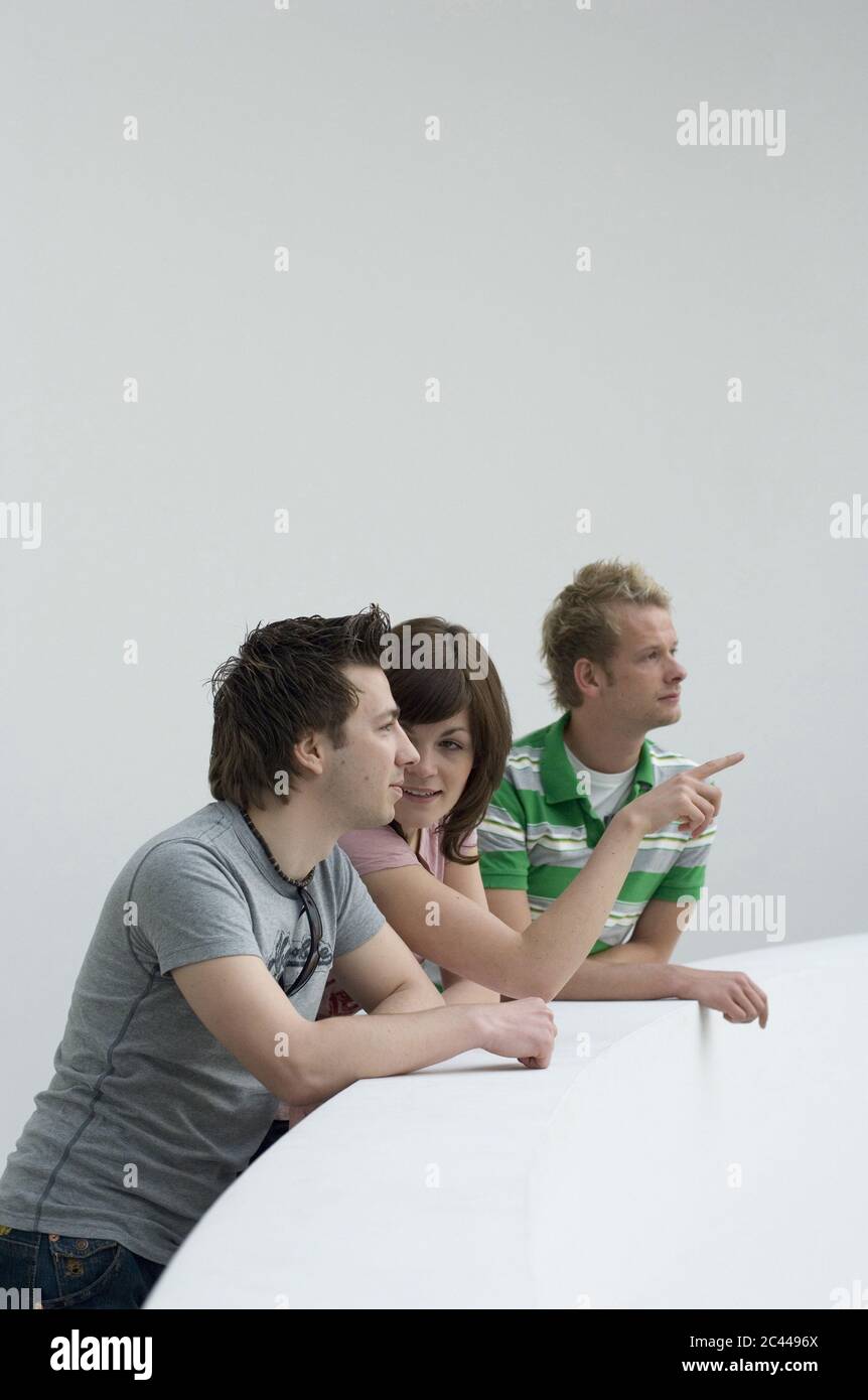 Three friends stand on a railing Stock Photo - Alamy