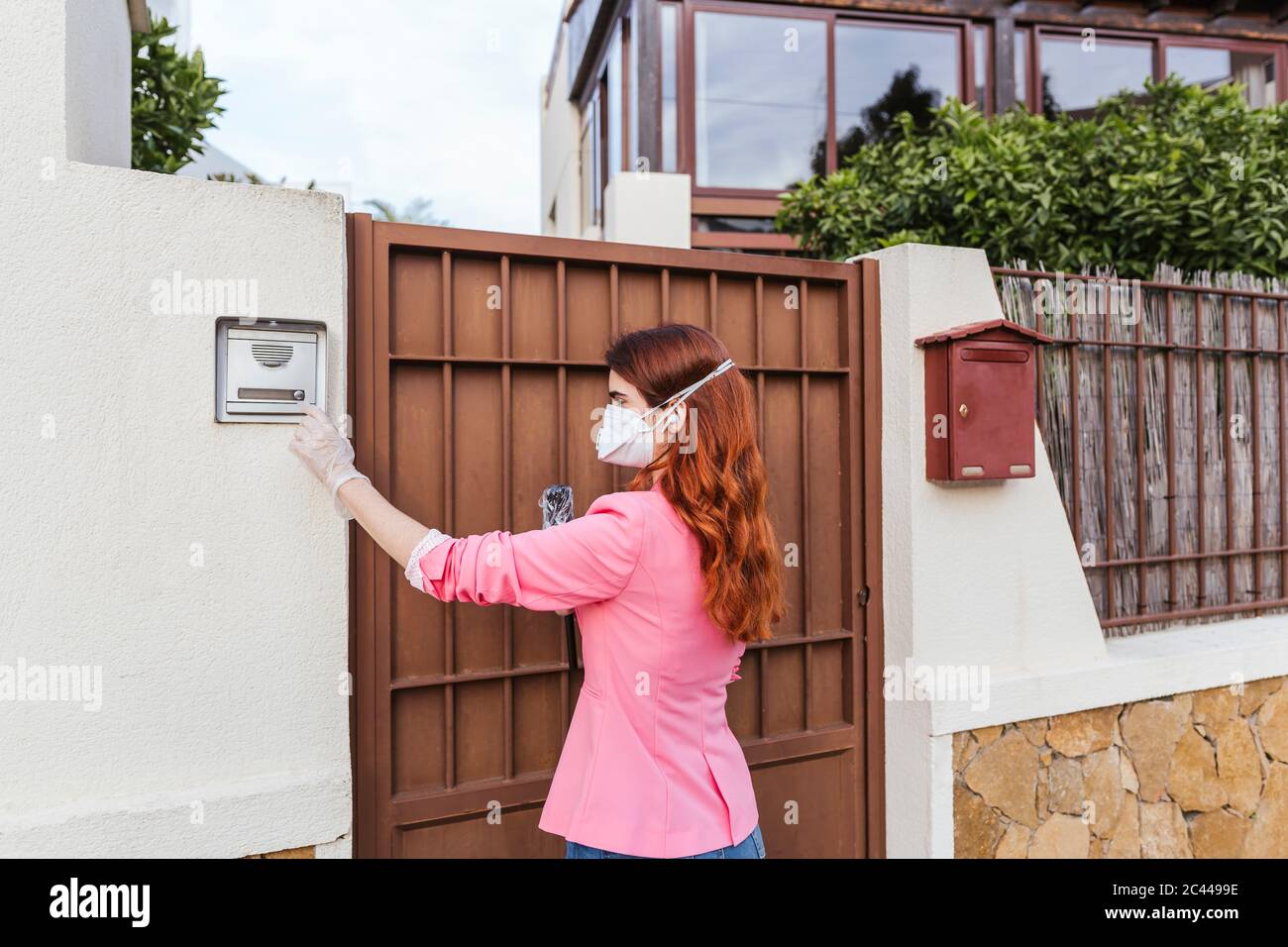 Female reporter wearing mask standing by closed gate Stock Photo - Alamy