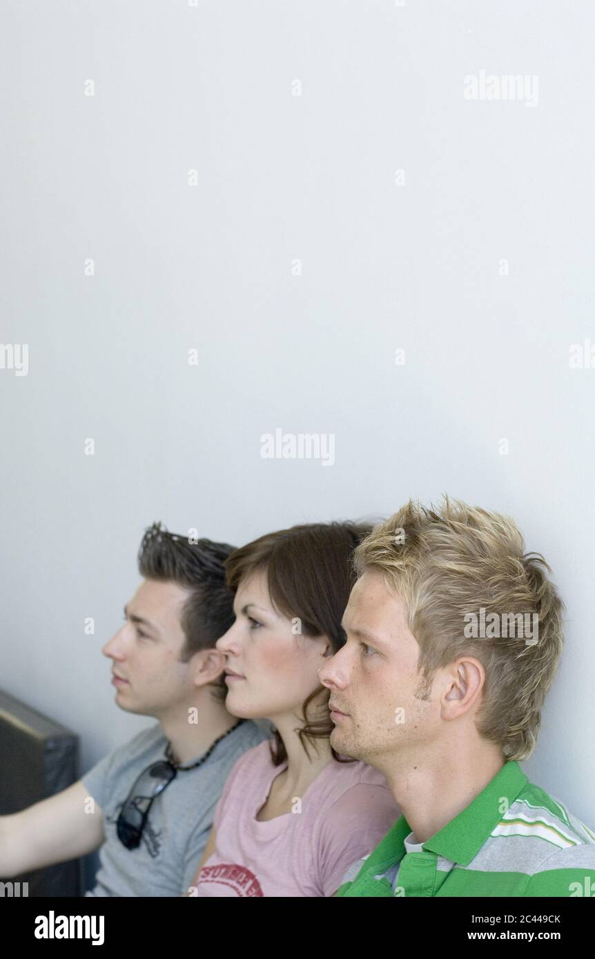 Three friends are sitting in a row Stock Photo - Alamy