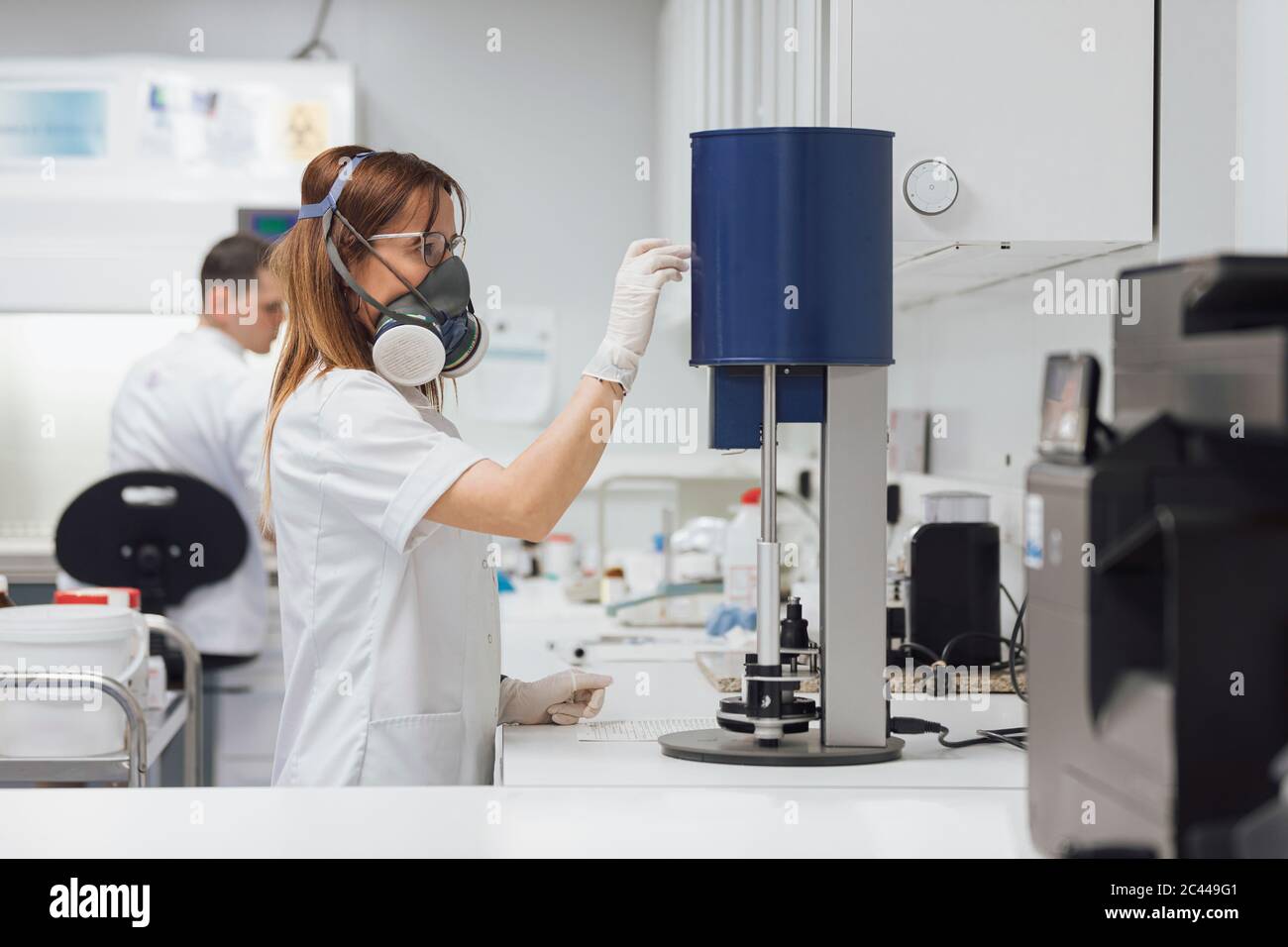 Female technician using medical equipment while male colleague working ...
