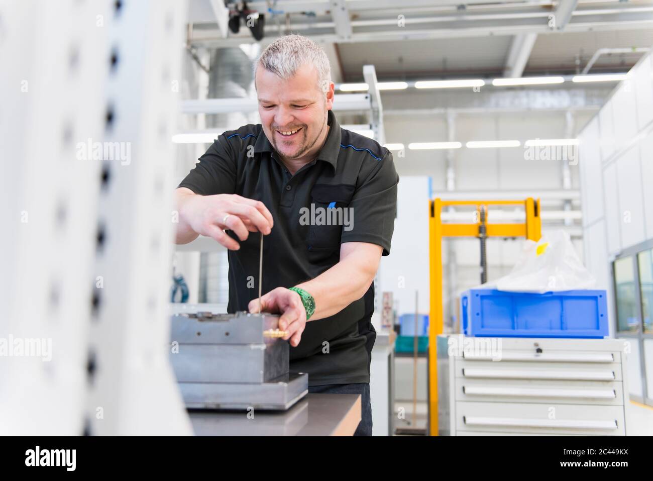 Smiling man working at workbench in a factory Stock Photo - Alamy