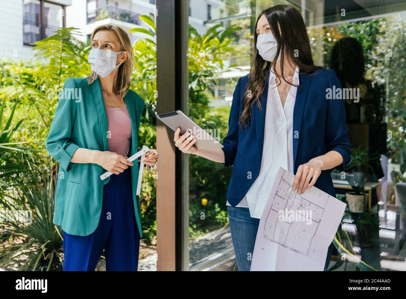 Two real estate agents wearing face masks while inspection outdoor area ...
