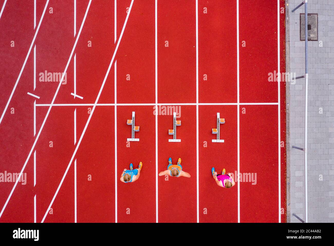 Aerial view three female sprinters standing track starting block hi-res ...