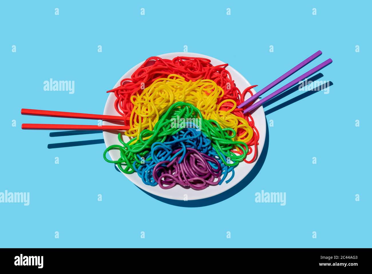 Plate of rainbow-colored spaghetti against blue background Stock Photo ...