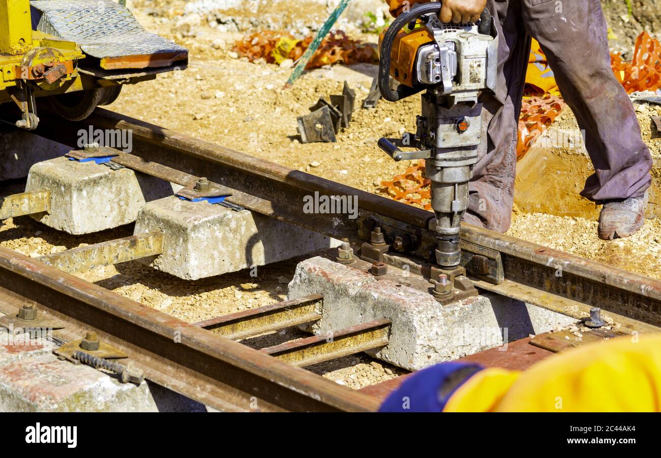 Railway workers bolting track rail. Detail worker with Light portable ...