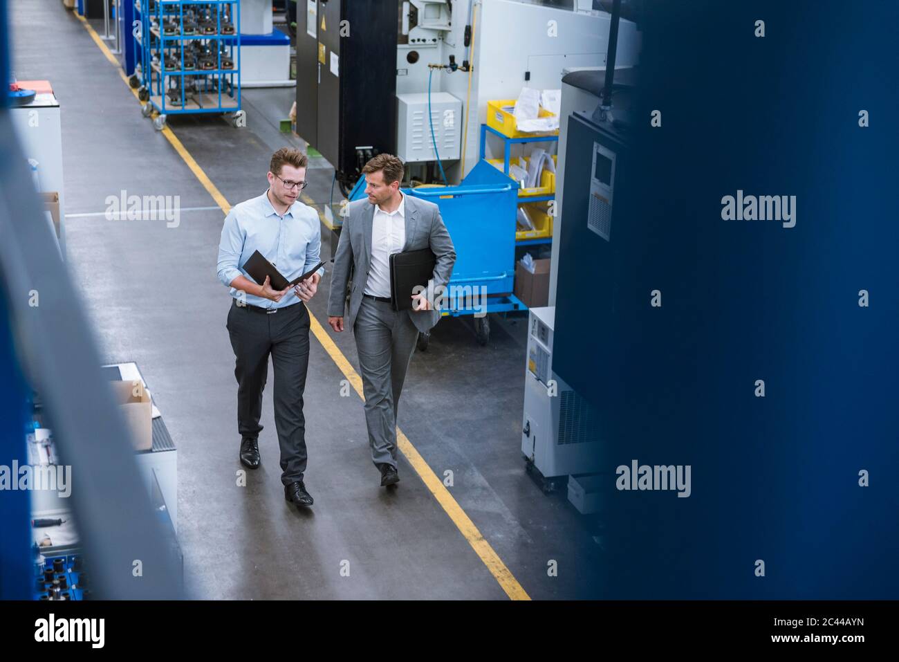 Two businessmen with clipboard walking and talking in factory Stock ...