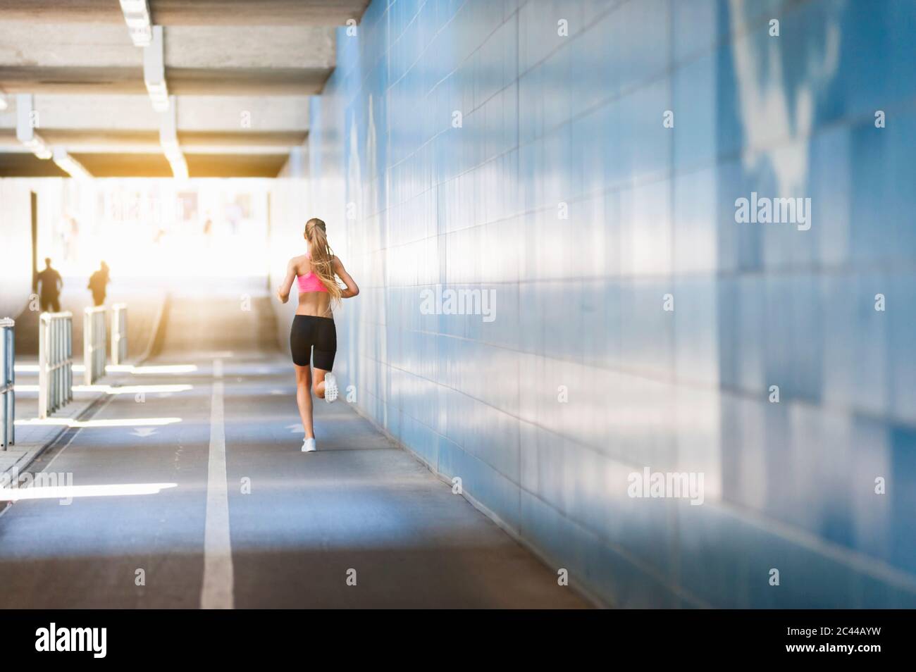 Rear view of female jogger in tunnel Stock Photo - Alamy