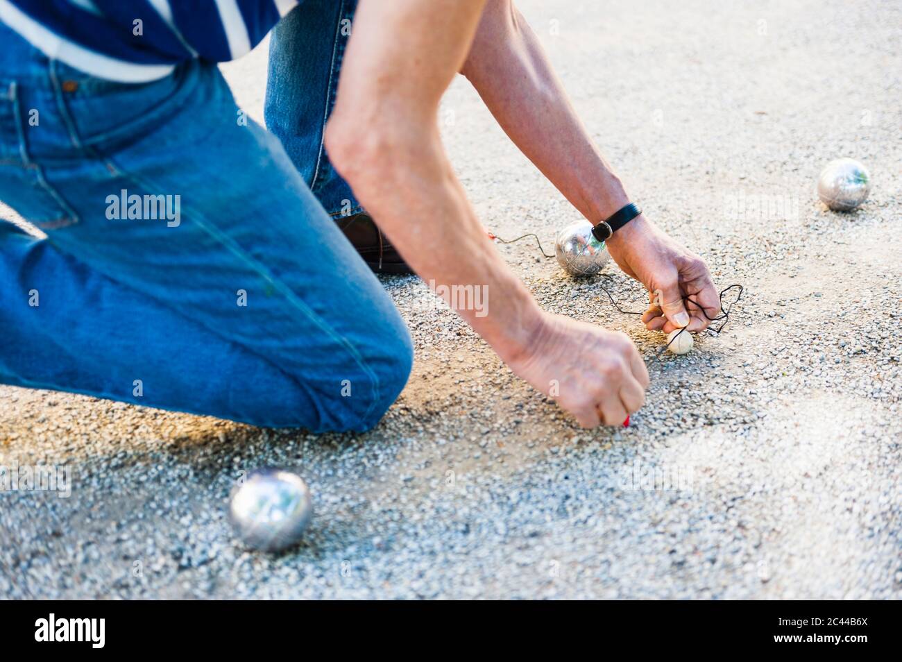 Crop view of kneeling boules player messuring gap between balls Stock ...
