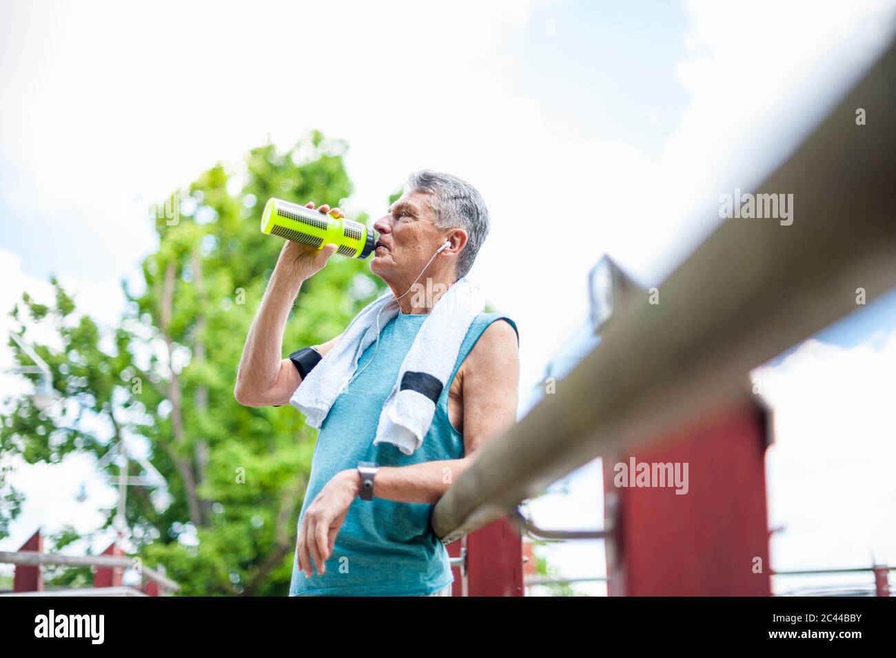 Low angle view of thirsty senior man drinking water from bottle while ...