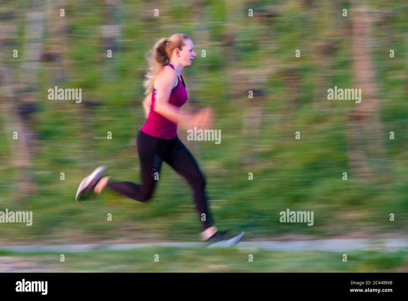 Full length side view of young woman sprinting at vineyard Stock Photo ...