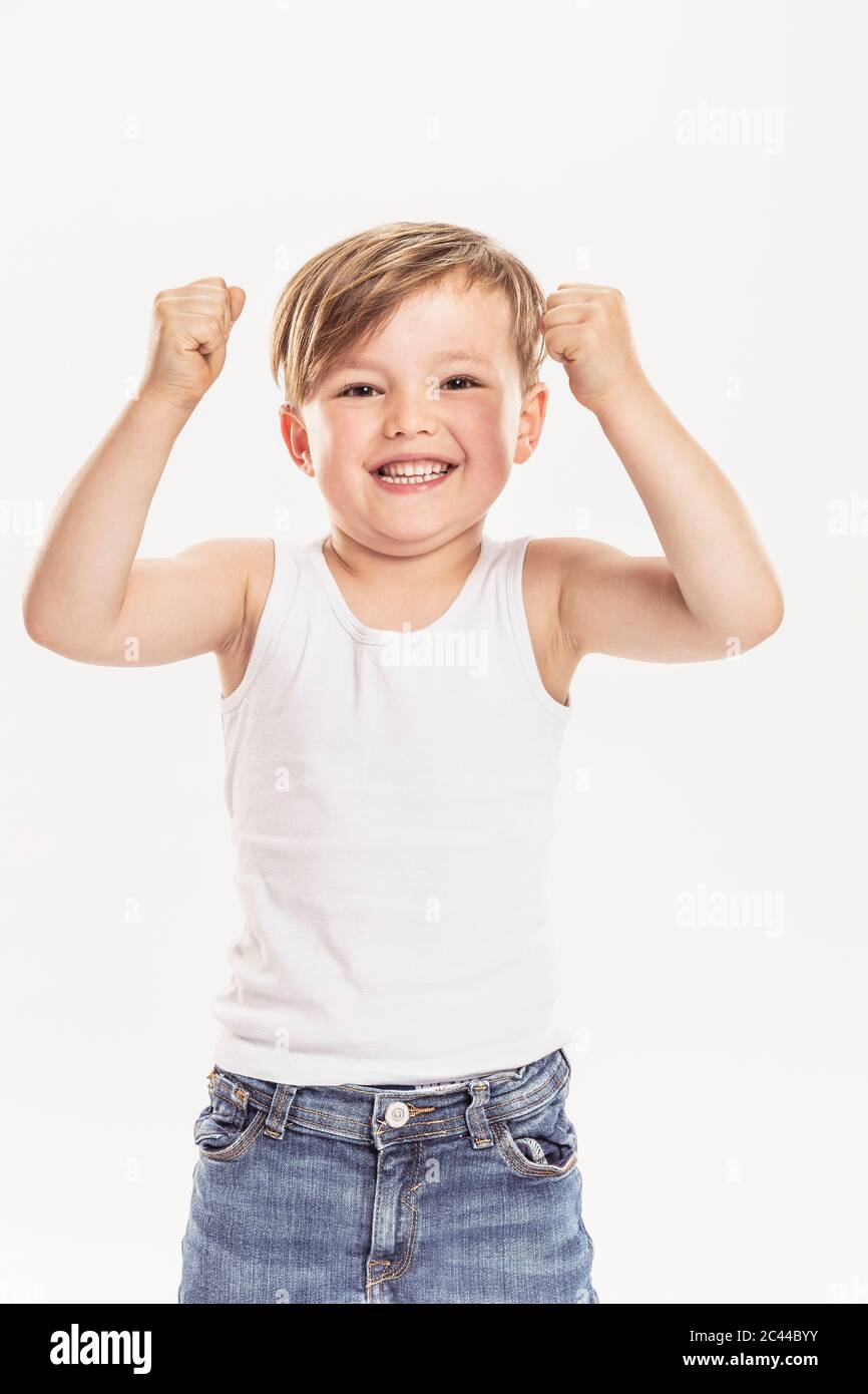 Portrait of little boy clenching fists standing in front of white ...
