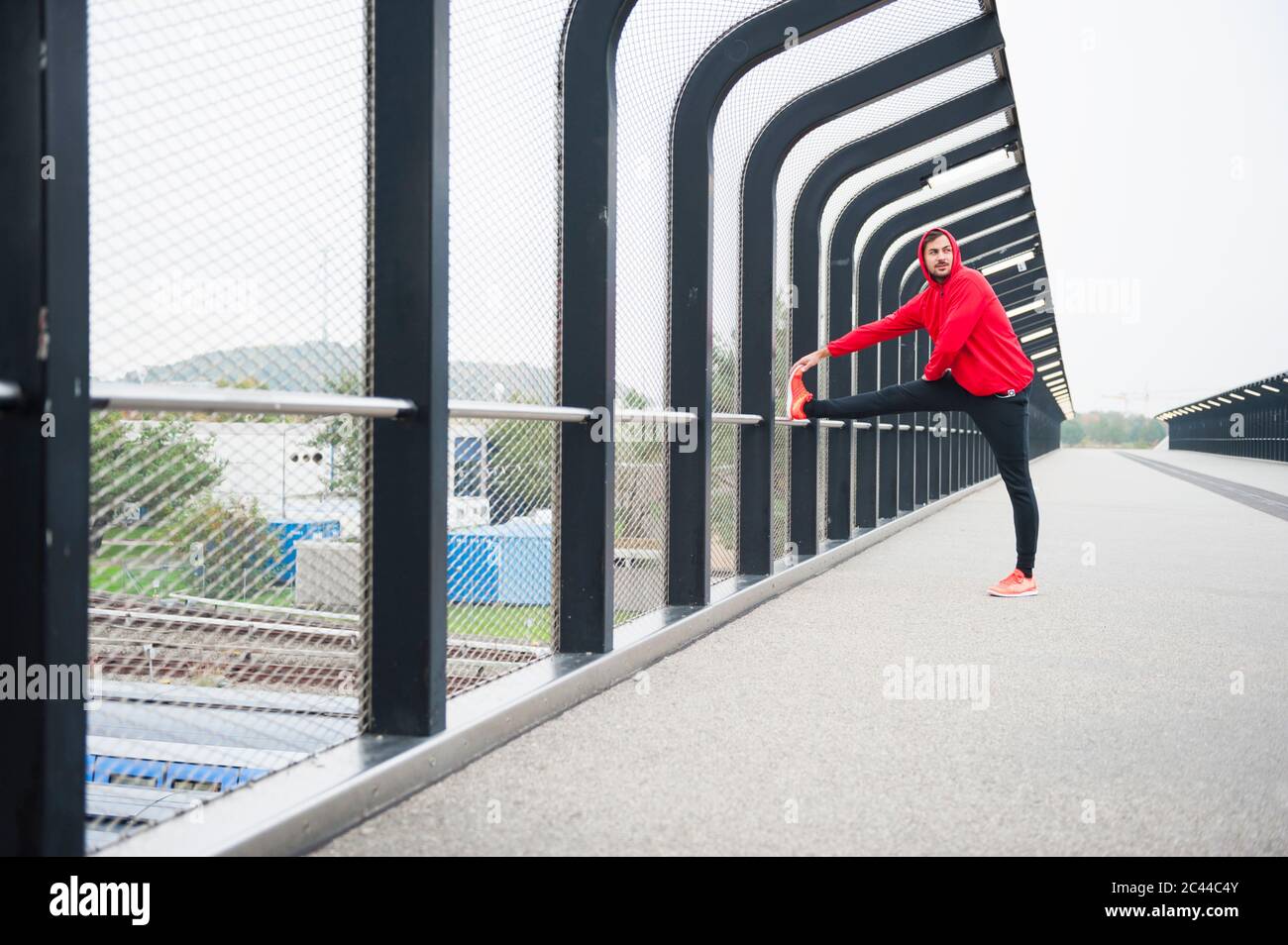 Young man stretching on a bridge Stock Photo - Alamy