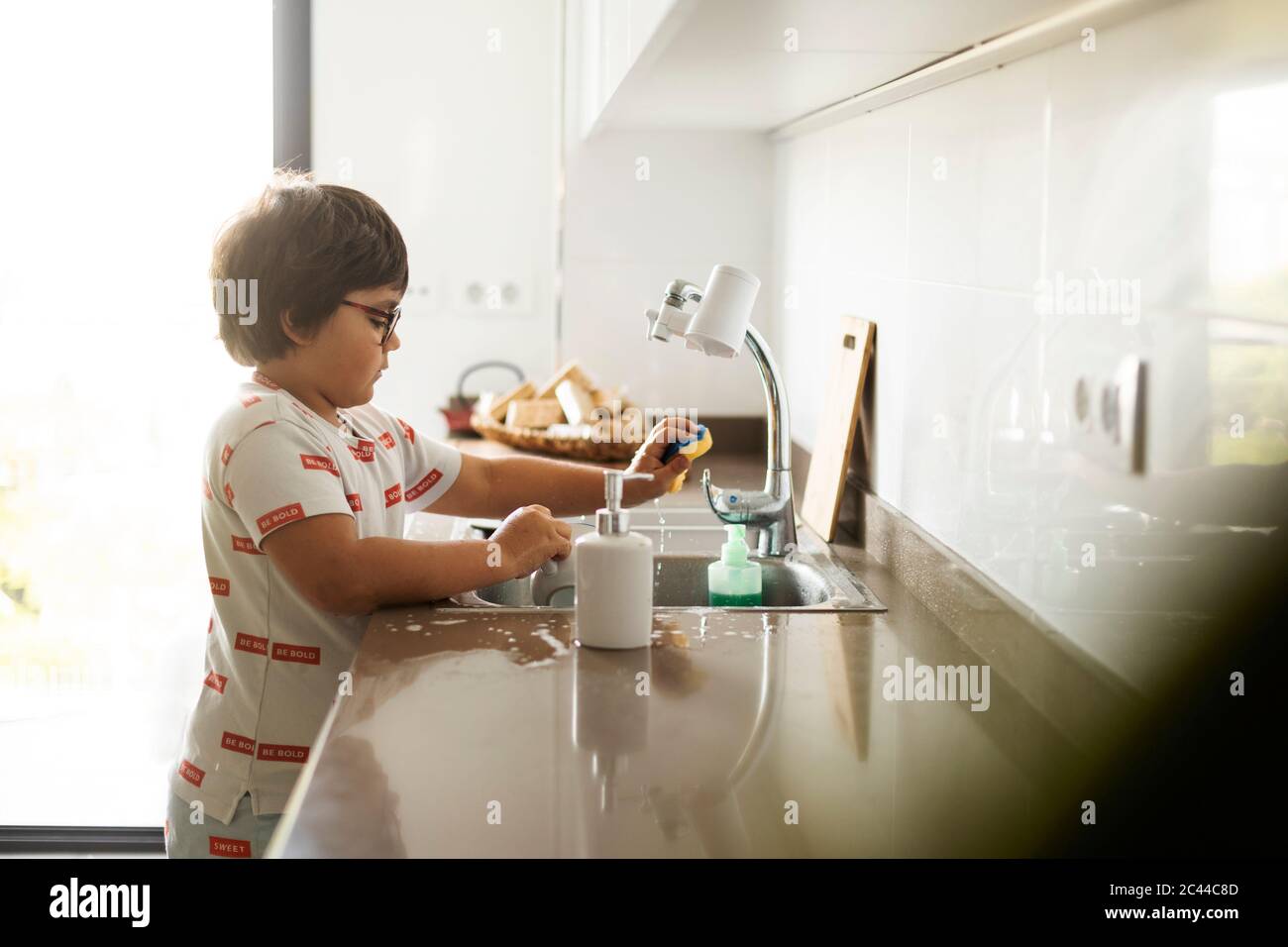 Boy washing dishes at home Stock Photo - Alamy