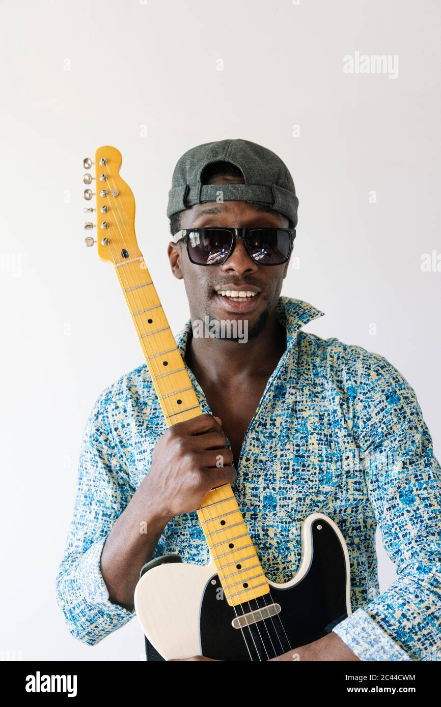 Portrait of confident musician holding guitar against white background ...