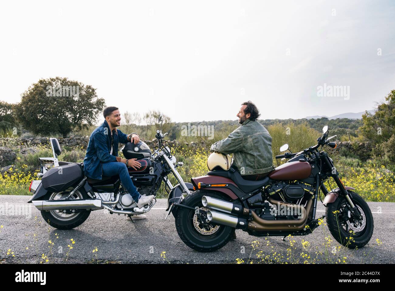 Male bikers talking while sitting on motorcycles against sky Stock ...