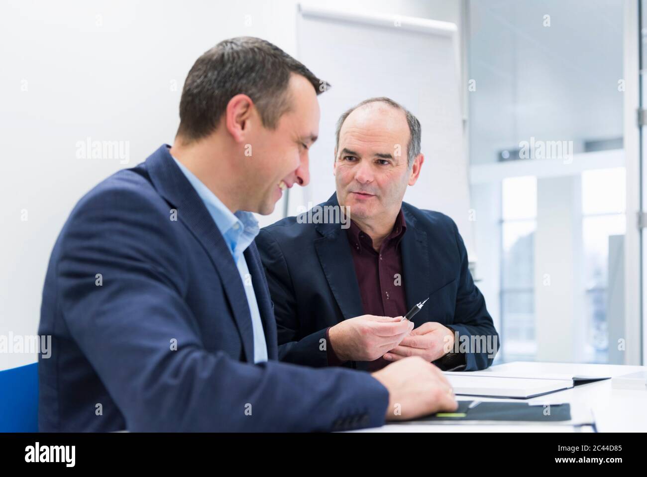 Two businessmen talking at desk in office Stock Photo - Alamy