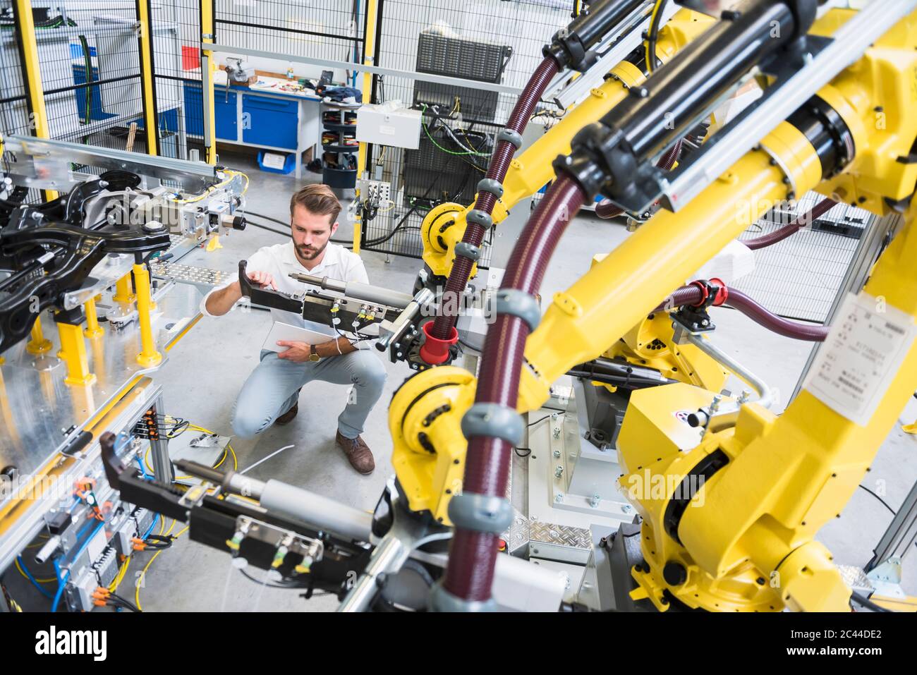 Full length of young engineer crouching while examining computer-aided ...