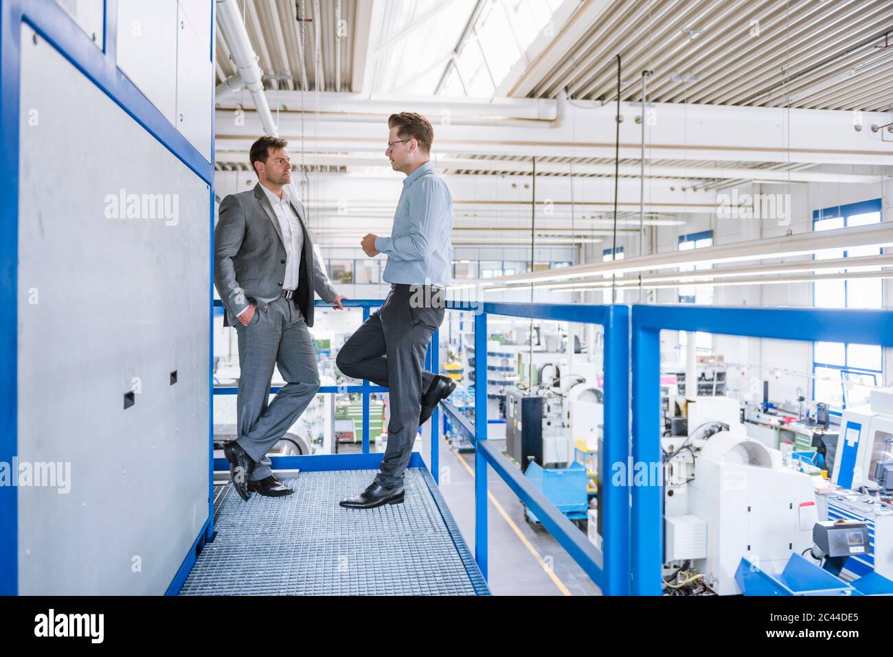 Two businessmen talking on upper floor in a factory Stock Photo - Alamy