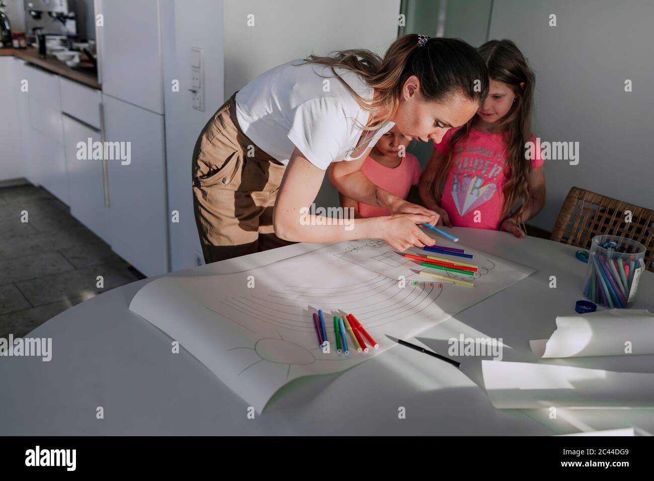 Mother assisting daughters in drawing on paper at home Stock Photo - Alamy