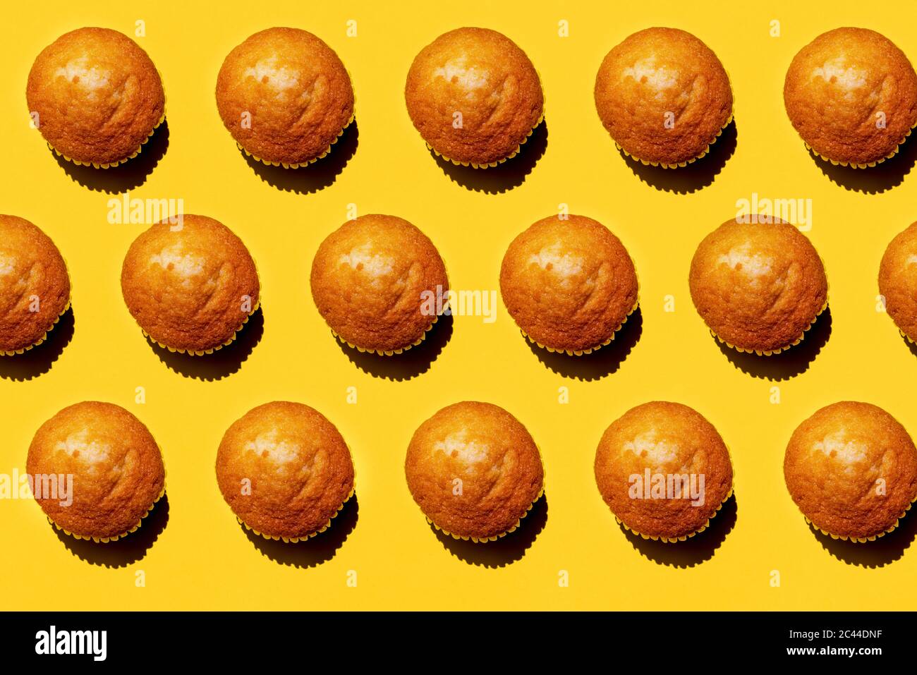Pattern of rows of muffins against yellow background Stock Photo - Alamy