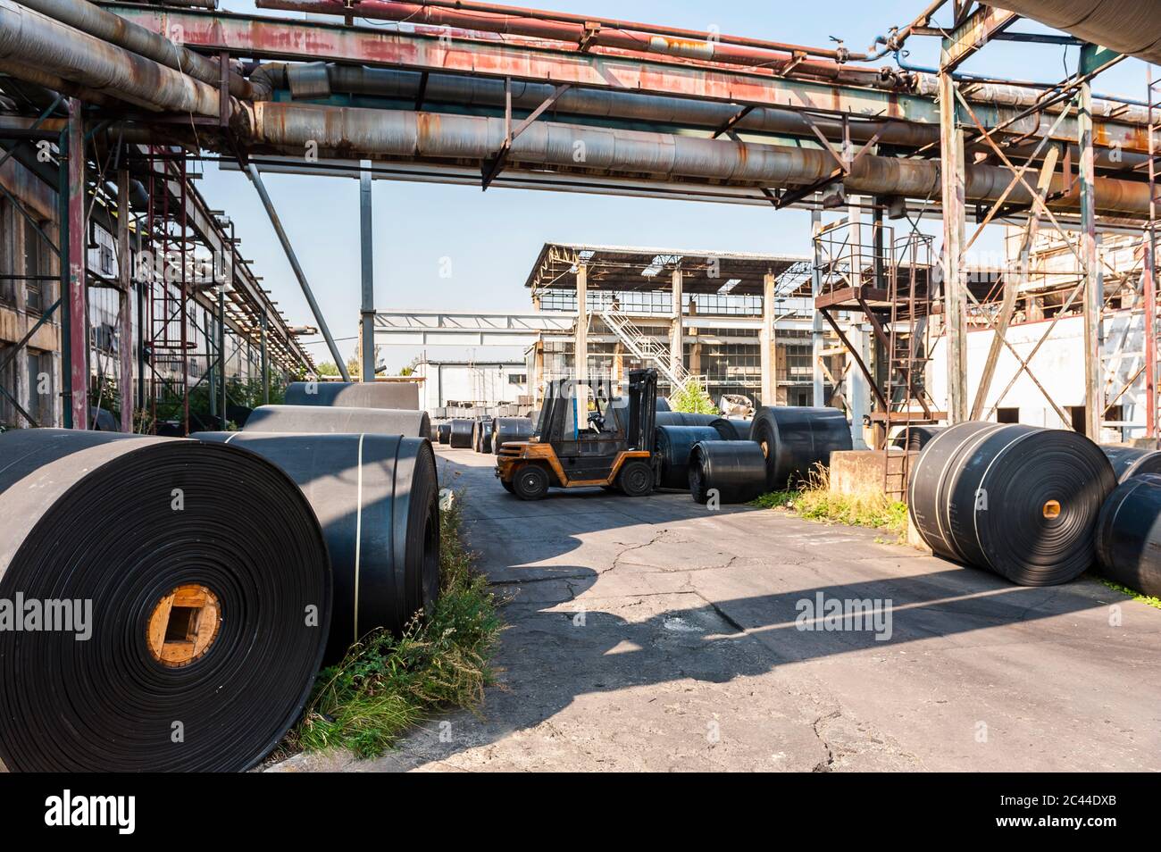 Rubber rolls and forklift on factory yard Stock Photo - Alamy