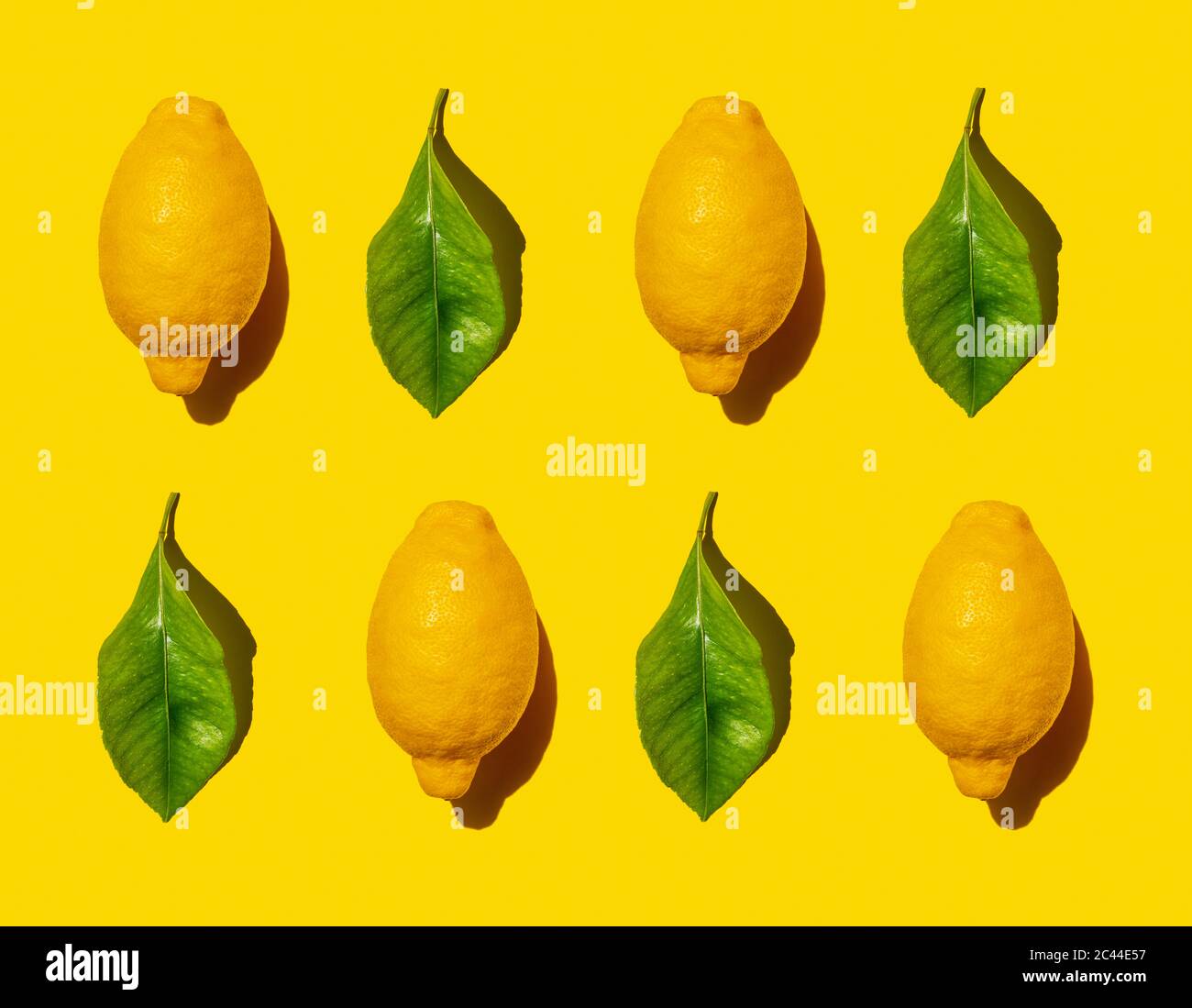 Pattern of ripe lemons and green leaves against yellow background Stock ...