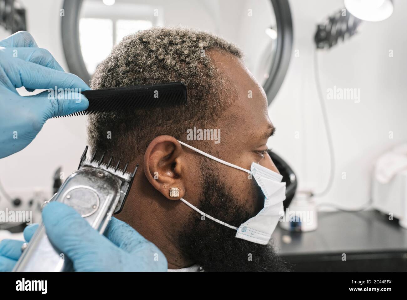 Barber wearing surgical mask and gloves doing hair of customer Stock ...