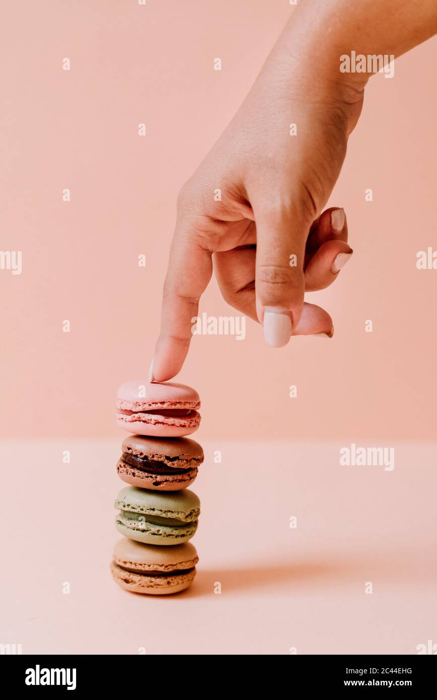 Female hand touching stack of macaroons on pink background Stock Photo ...