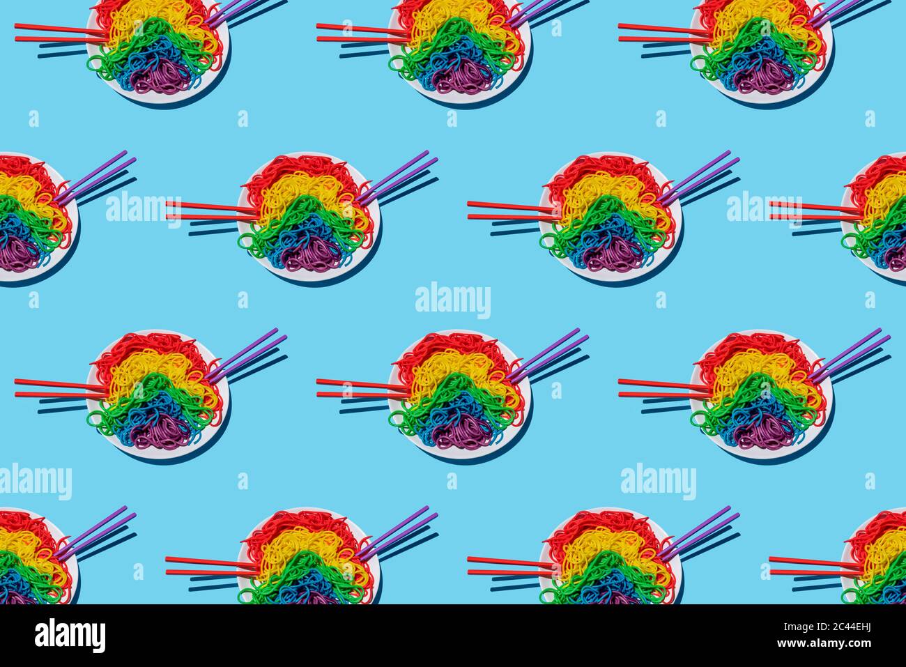 Pattern of plates with rainbow-colored spaghetti against blue ...