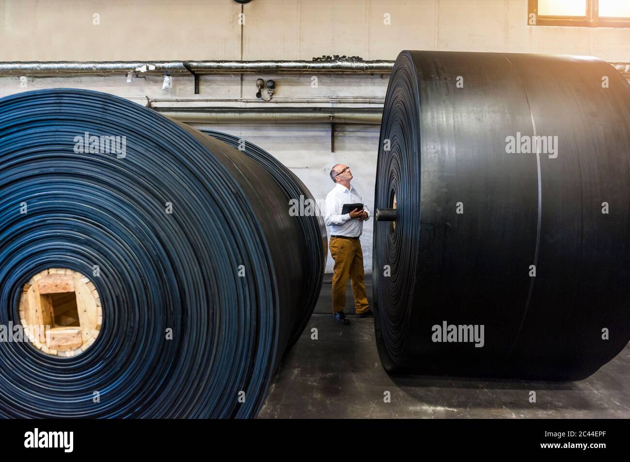 Senior businessman checking product in a rubber processing factory ...