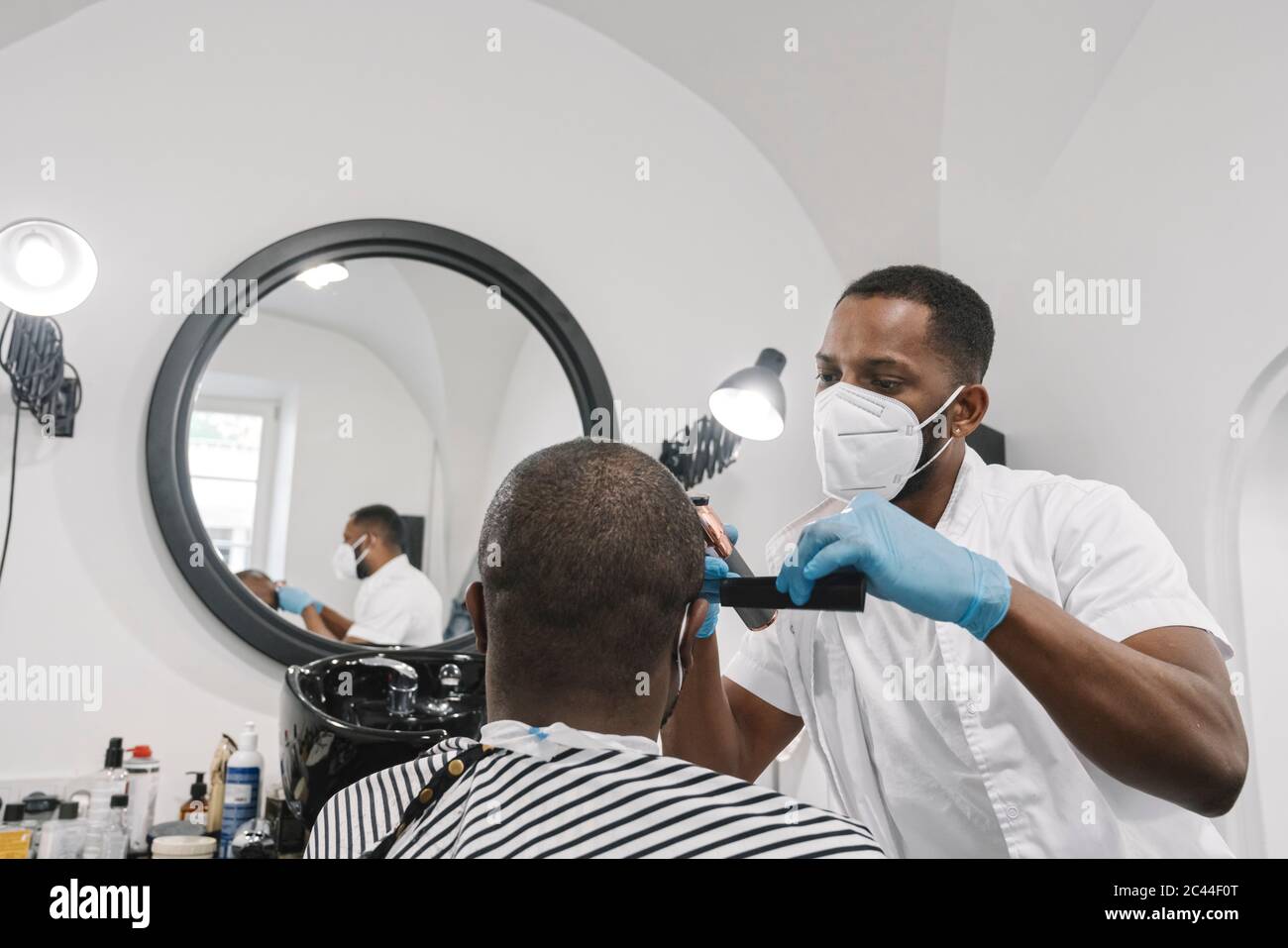 Barber wearing surgical mask and gloves cutting hair of customer Stock ...