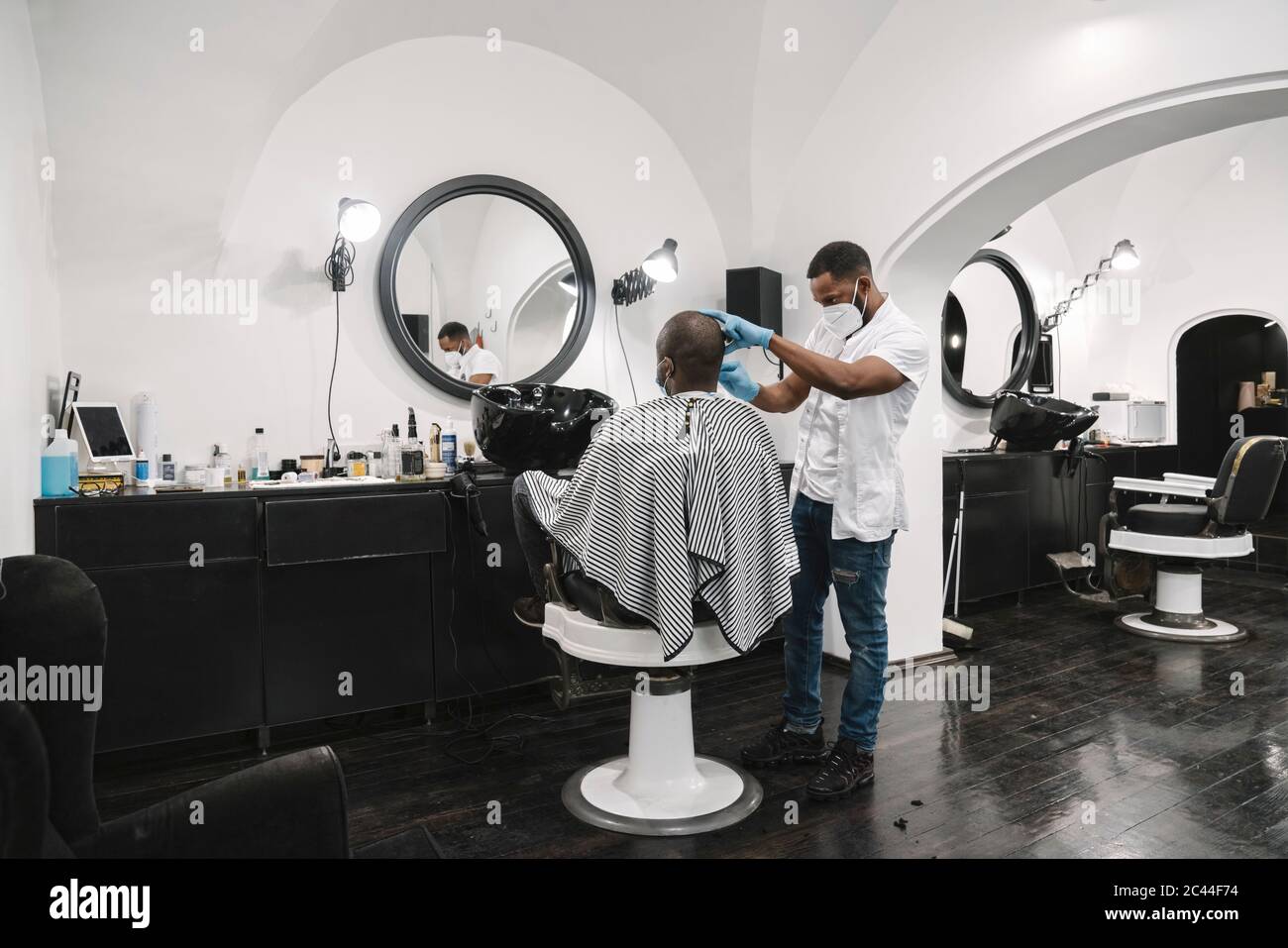 Barber wearing surgical mask and gloves cutting hair of customer Stock ...
